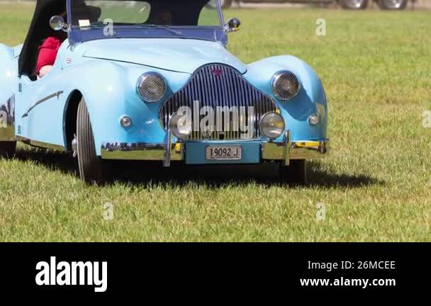 Classic blue car driving across grass field Stock Video Footage - Alamy
