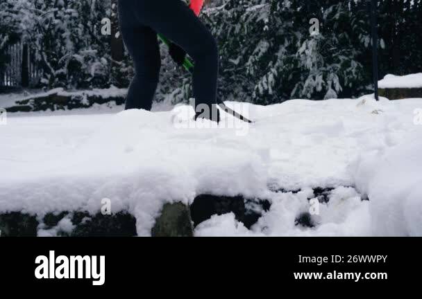 Woman clearing path after snow fall in winter medium 4k shot selective ...