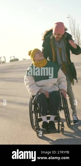 Happy disabled person enjoying a stroll with friend, demonstrating the ...