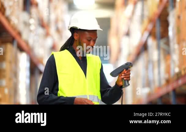 Warehouse worker wearing safety vest and helmet scanning packages with ...