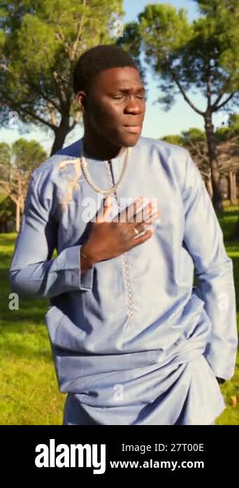 Senegalese male standing confidently in park, wearing vibrant blue and ...