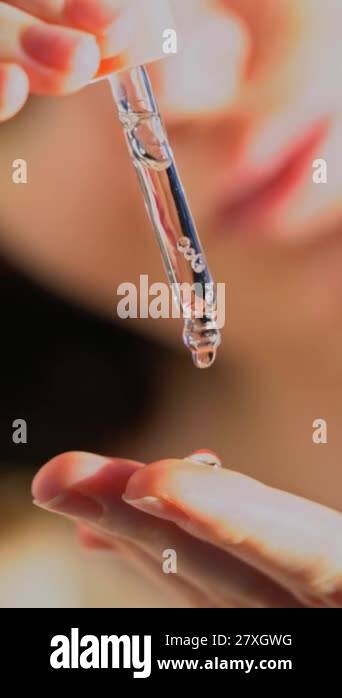 Vertical screen: Woman holding a dropper with serum for face. Facial ...