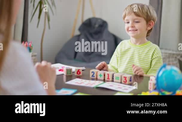 Smiling young boy in striped shirt high-fives an adult during an ...