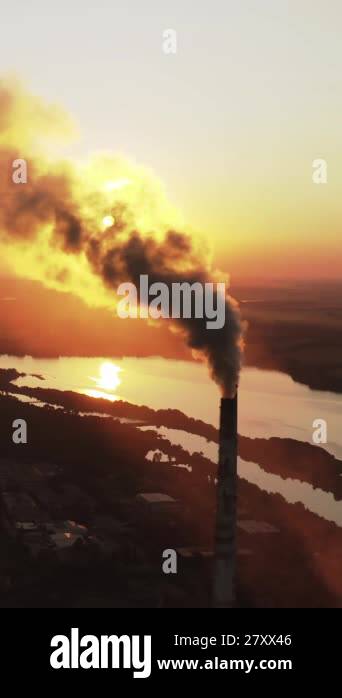 Pipes pollute atmosphere with smoke against the setting sun. Ecology ...