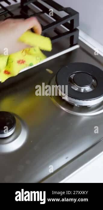 Cleaning kitchen gas stove. Womans hand cleaning gas stove with sponge ...