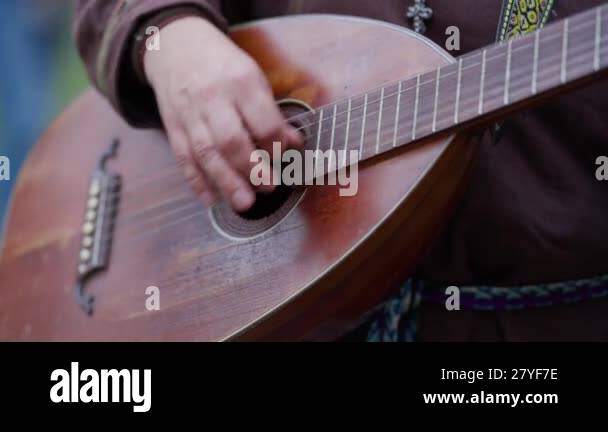 A person is playing a guitar with a wooden body. The guitar is an old ...