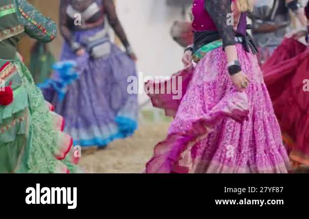 A group of women are dancing in a field wearing colorful clothing ...