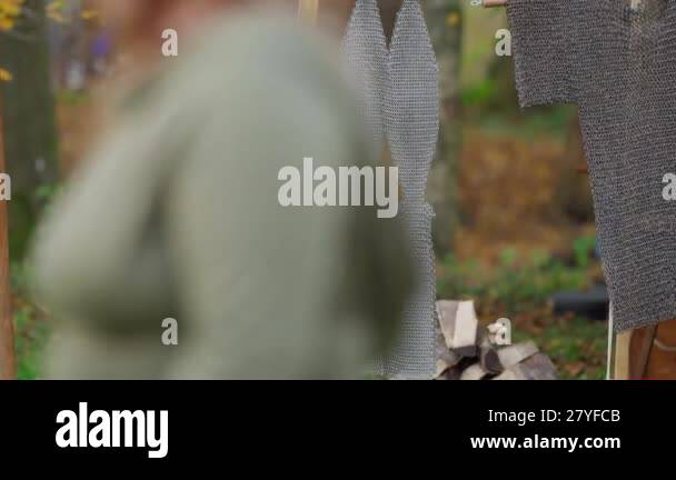 A woman is walking past a wooden structure with a metal object hanging ...