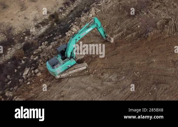 Overhead view of excavator working by digging the soil of agricultural ...