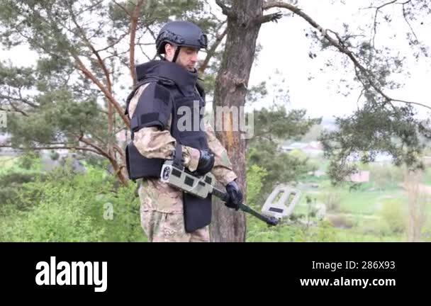 A man in a military uniform and bulletproof vest works in the forest ...