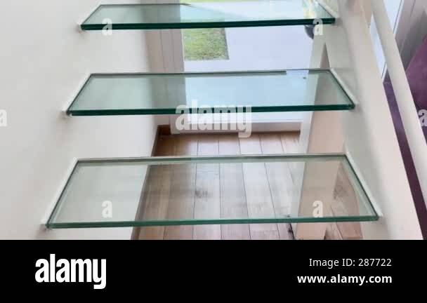 Modern glass stairs with a view of a backyard and a barbecue grill ...