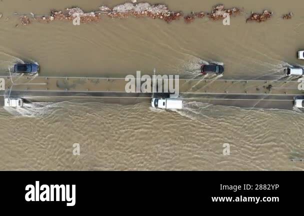 cars and trucks driving along a flooded highway during floods and ...