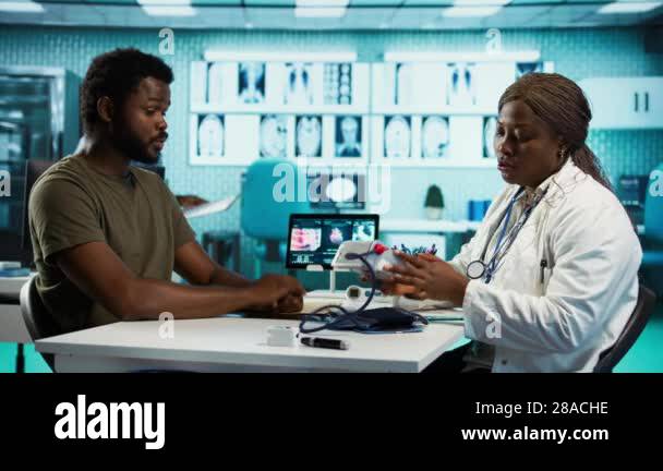 Black medic measuring the blood pressure and pulse of a male patient ...