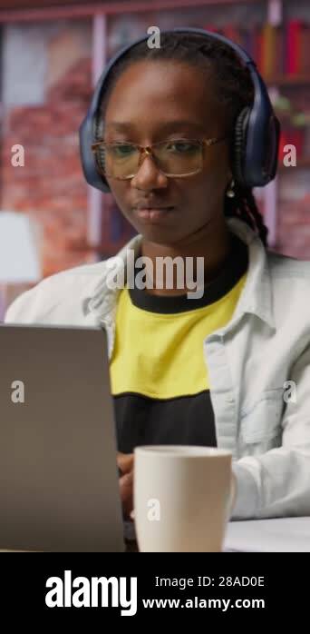 Vertical video Teleworker listening music while typing on notebook keyboard in home office ...