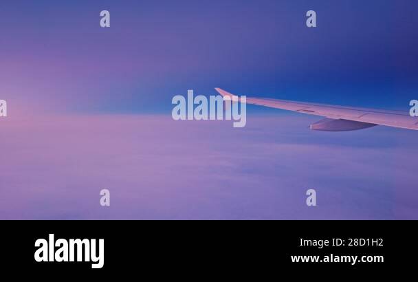 Airplane flying over color sky clouds during scenic sunset or sunrise ...