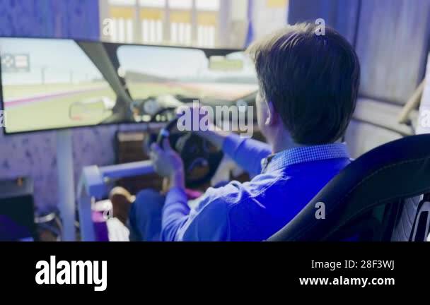Man sitting at racing simulator driving game with immersive multi ...