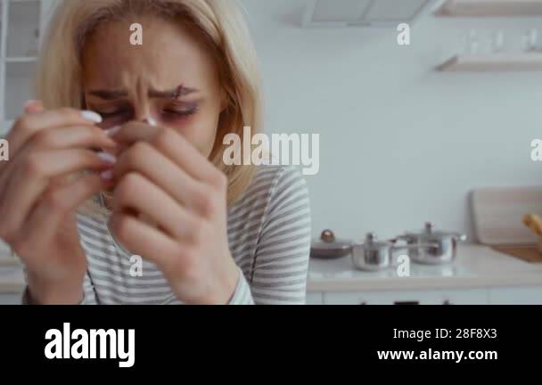 A young woman is visibly distressed while alone in her kitchen ...