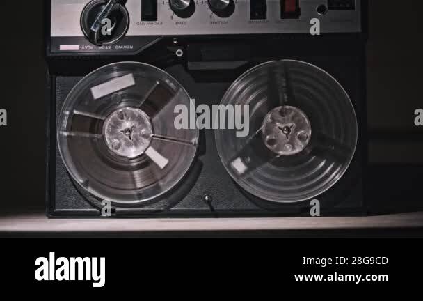 A classic reel-to-reel tape recorder with turning spools, evoking a ...