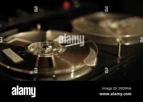 Close-up shot of spinning reels on a reel-to-reel tape deck. Mechanical ...