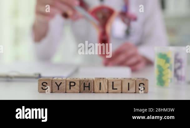 Word Syphilis from cubes against doctor showing uterus model ...