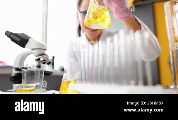 A dedicated scientist in a lab using beakers and a microscope for ...