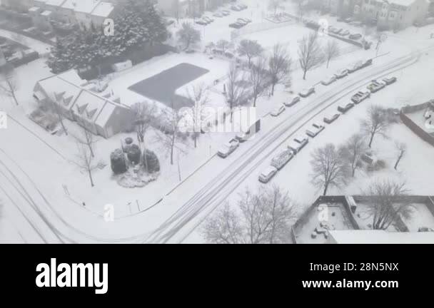 Blizzard, residential homes and trees during winter snowfall. Lone cars ...