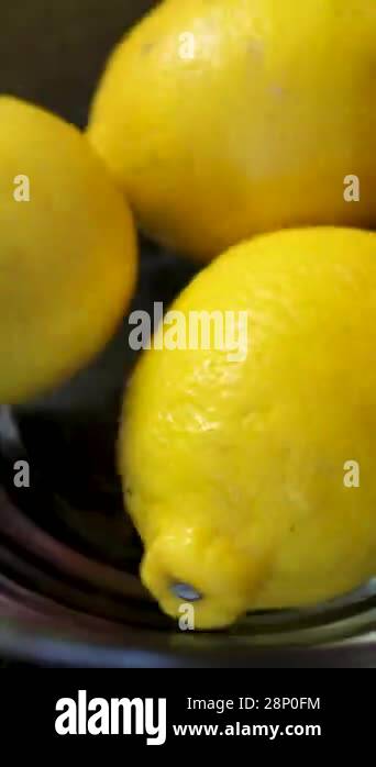 Fresh lemons in a glass bowl at a bar, with a variety of bottles in the ...