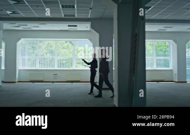 Confident couple walking office building in suits. Corporate colleagues ...