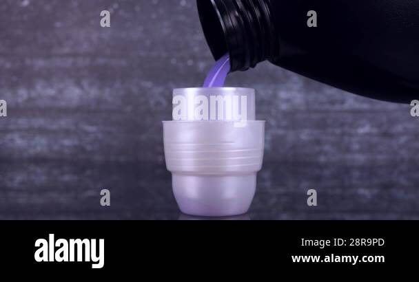 Purple liquid detergent flowing from the bottle into the container on ...