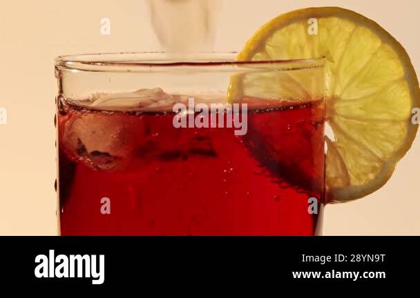Ice Dropped Into Red Carbonated Drink In Clear Glass With Lemon Slice Stock Video Footage - Alamy