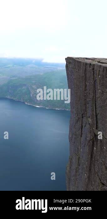 Explore the majestic landscape of Norway as a towering cliff juts into ...