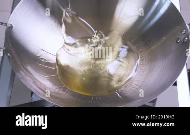 Vegetable oil flowing from a plastic bottle with a yellow cap into a ...