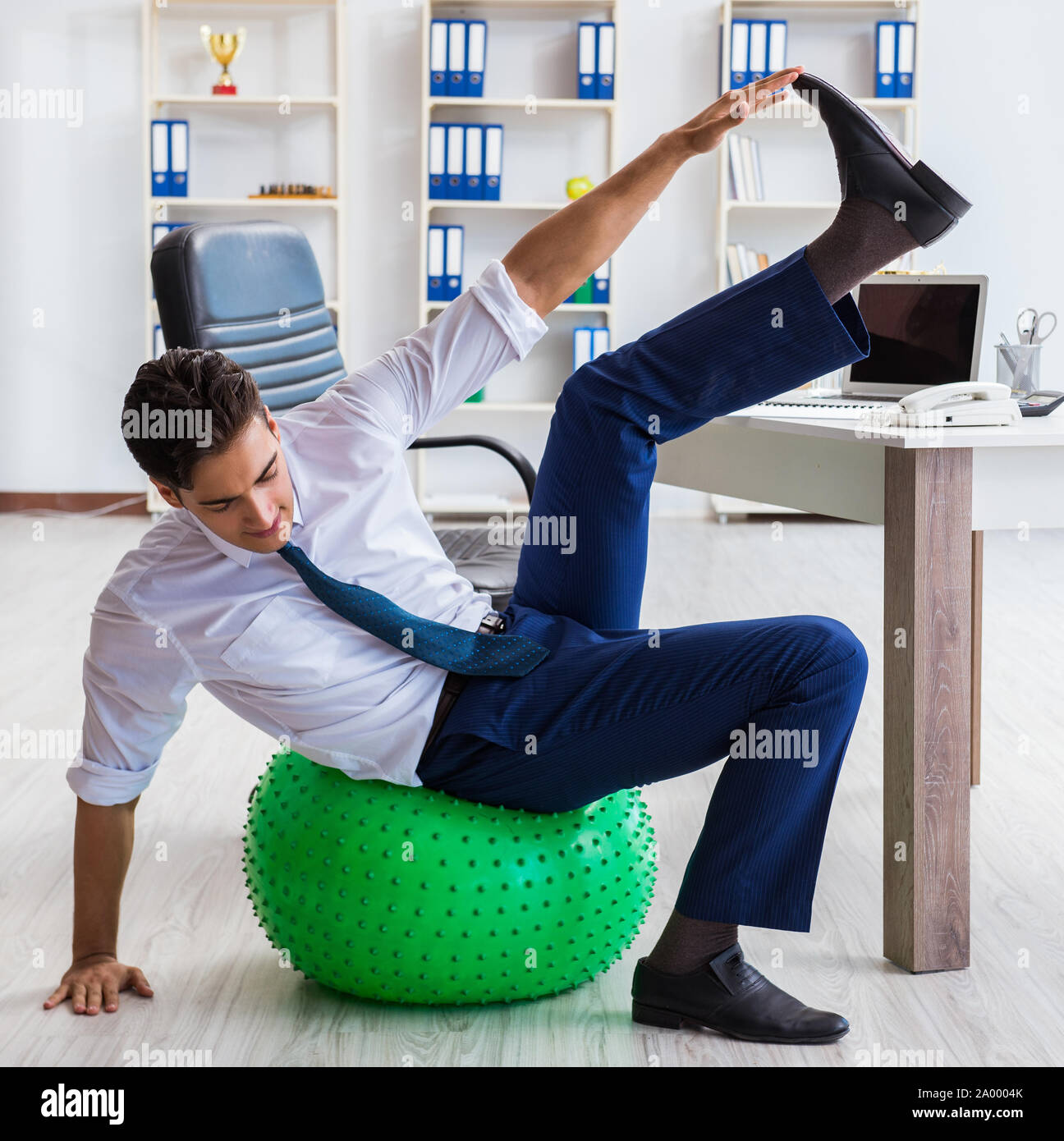 The young businessman doing sports stretching at workplace Stock Photo ...