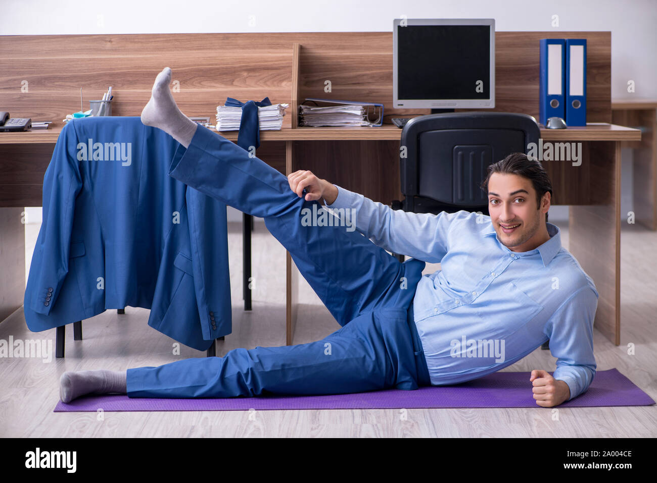 The young handsome businessman doing exercises at workplace Stock Photo ...