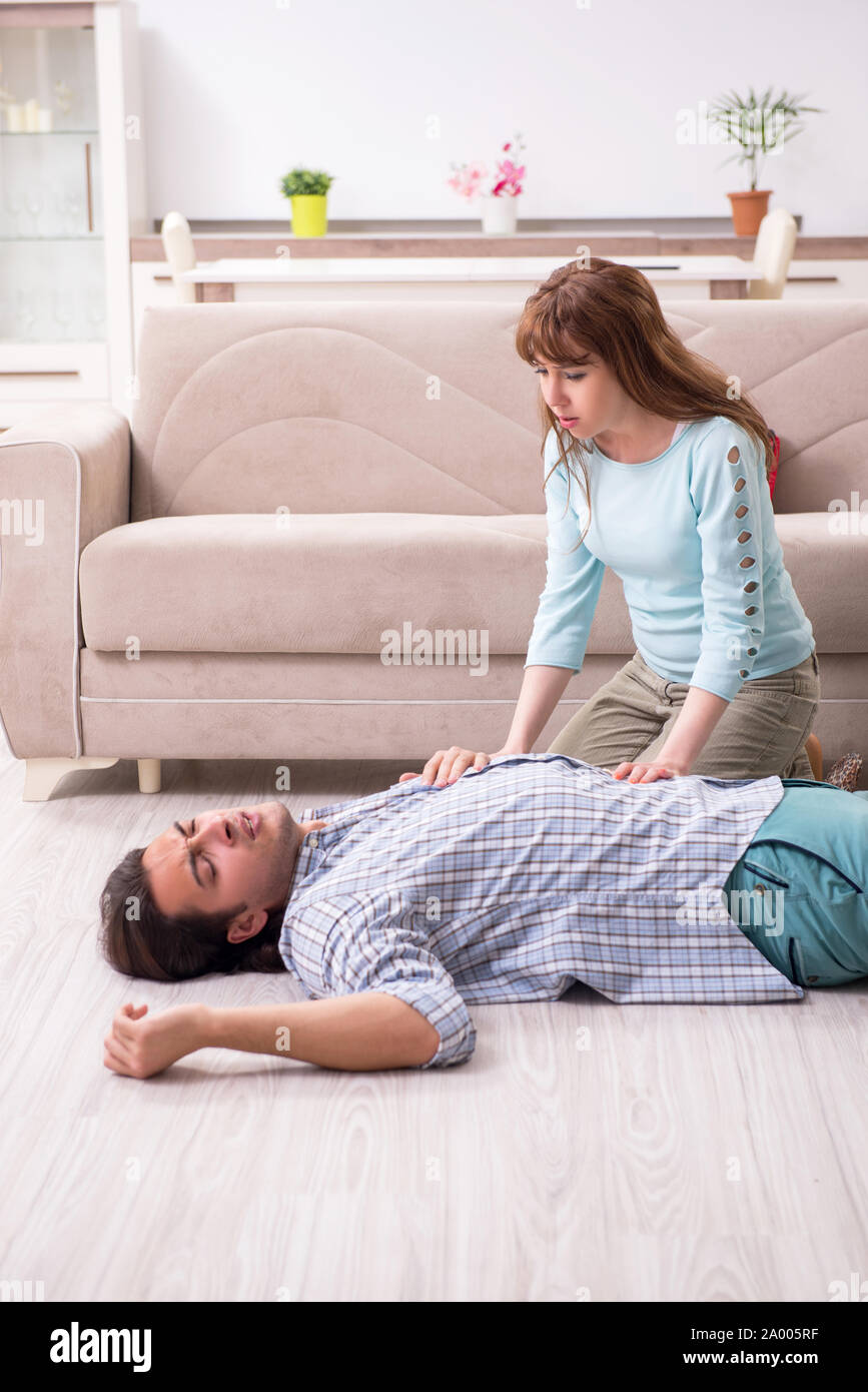 The young couple in first aid concept at home Stock Photo - Alamy