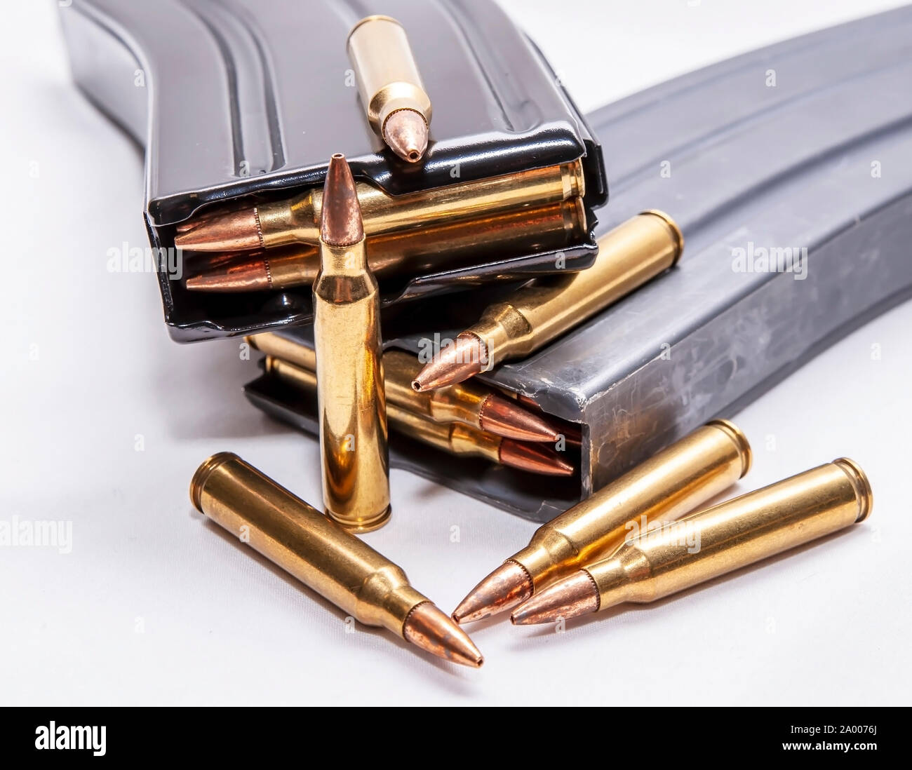 Two loaded rifle magazines with 223 caliber bullets around them on a ...