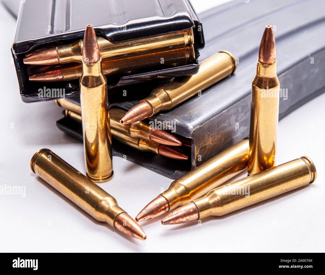 Two loaded rifle magazines with 223 caliber bullets around them on a ...