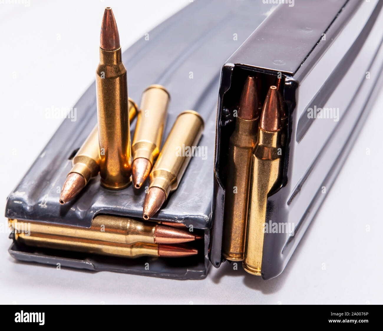 Two loaded rifle magazines with 223 caliber bullets around them on a ...