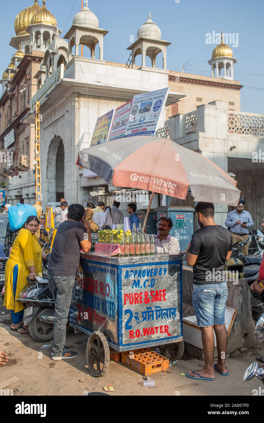 People standing around a vendor selling drinks from his cart outside a ...