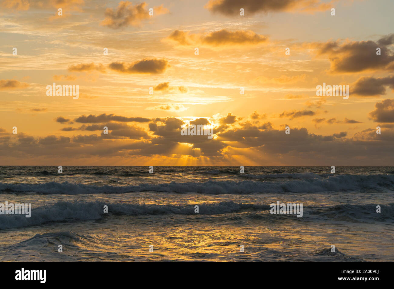 Beautiful sunrise cloudscape over ocean background. Sun rays beaming ...