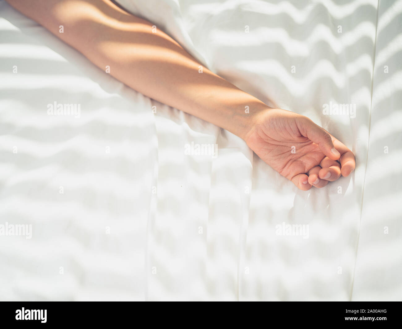 The hand of a young woman relaxing on a bed in the sunshine Stock Photo ...