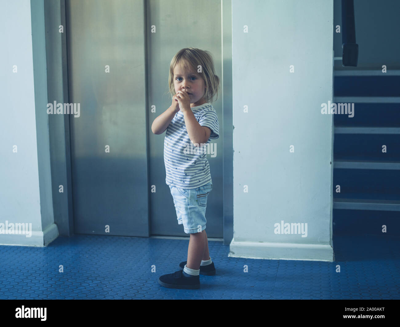 A little toddler is standing in the hallway waiting for the lift Stock ...