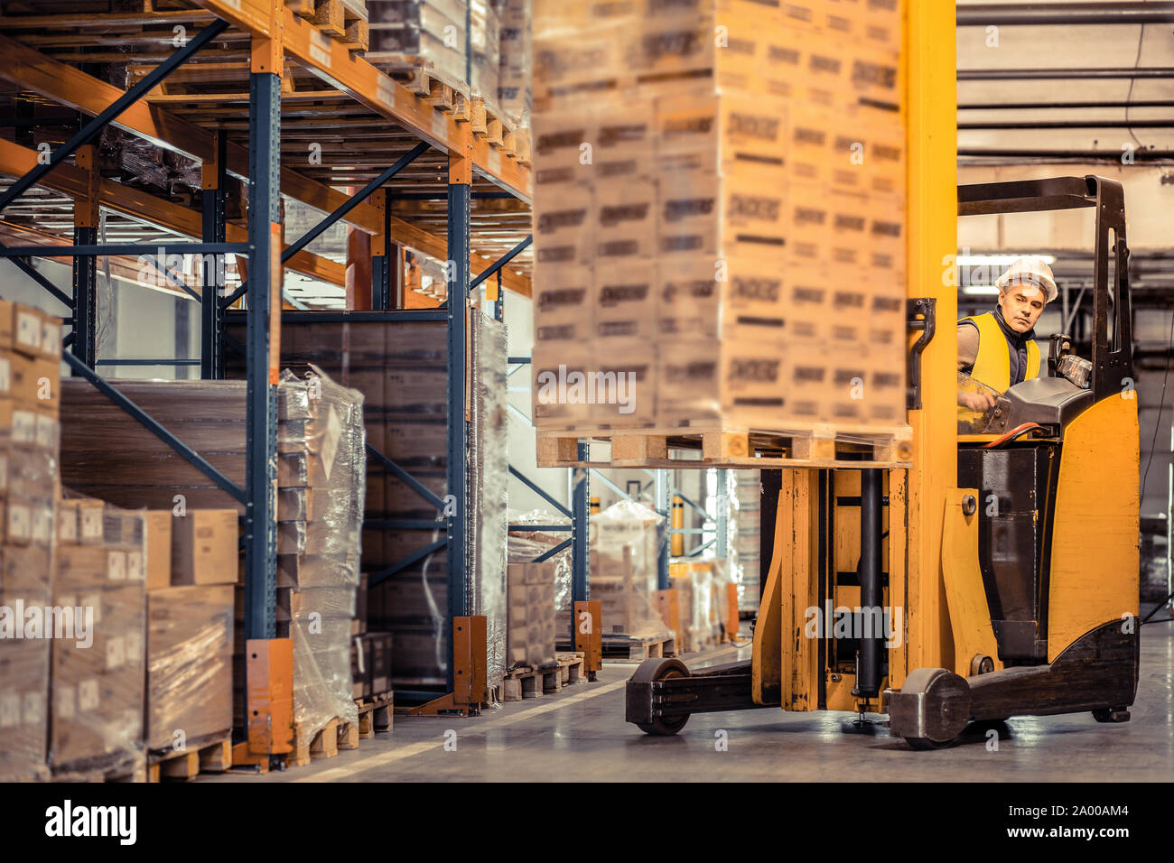 Attentive man putting pale of boxes on support Stock Photo - Alamy