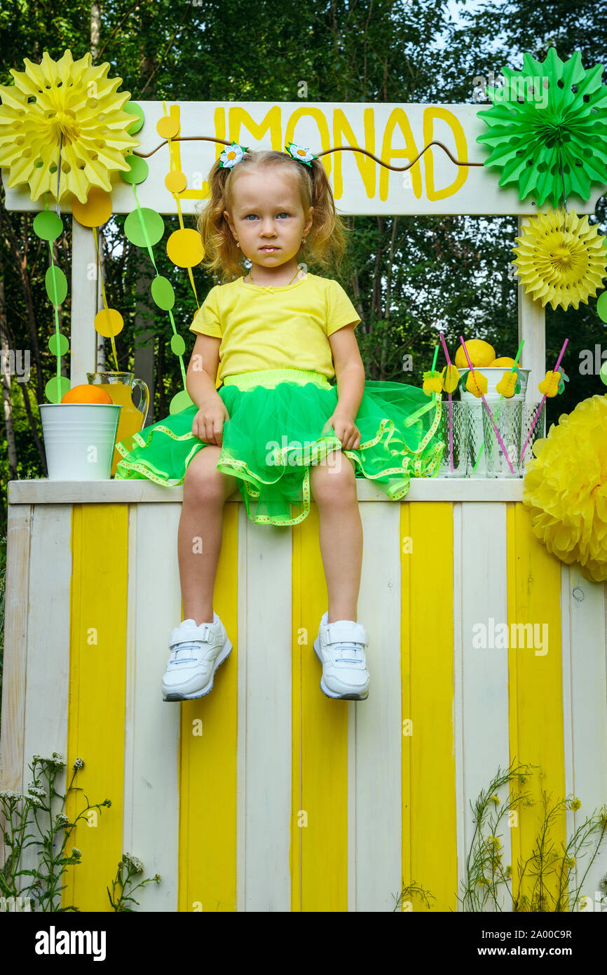 Little girl sitting on lemonade stand in park in summer day Stock Photo ...