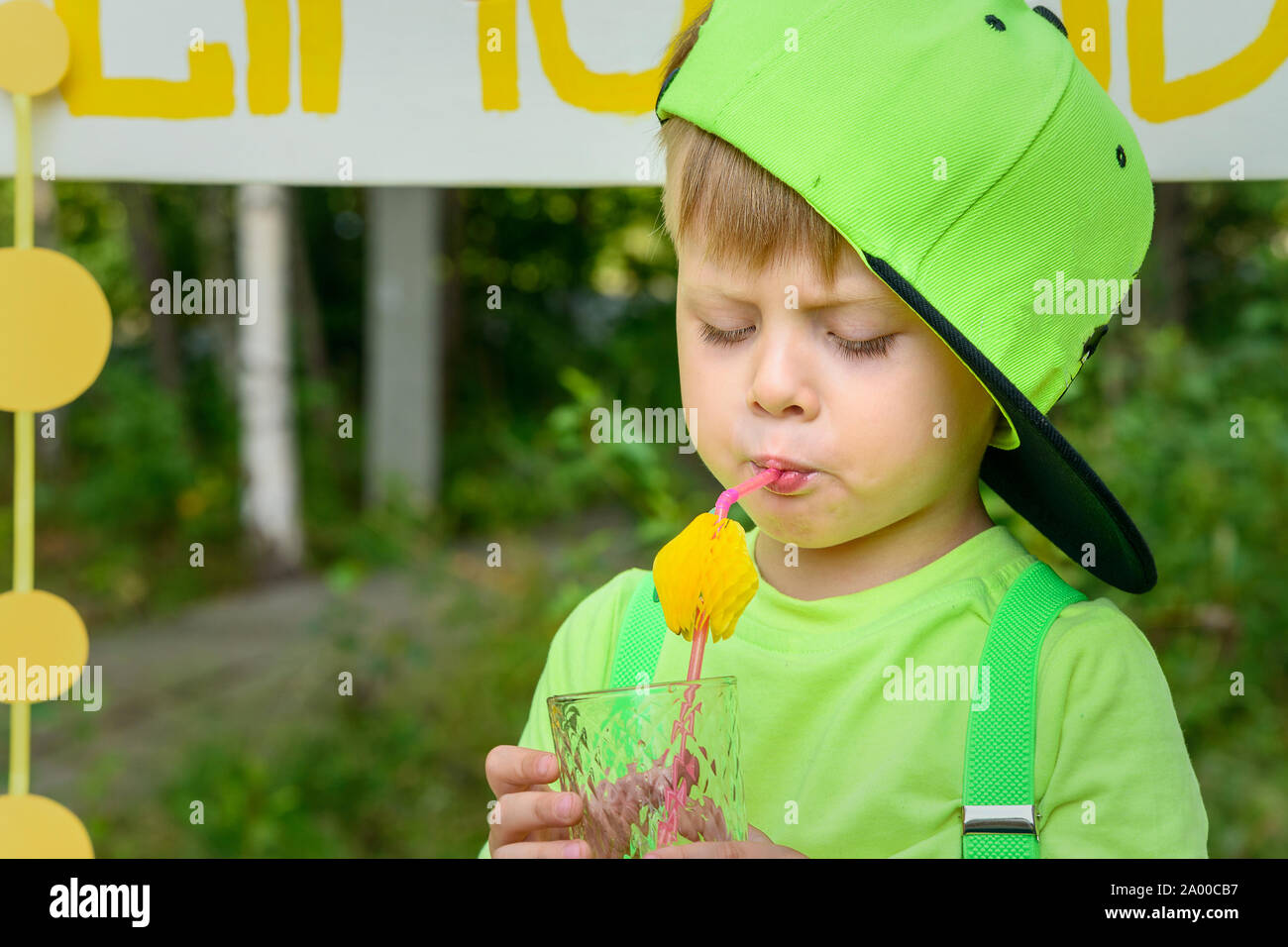 Little boy drinking lemonade on lemonade stand in park in summer day ...