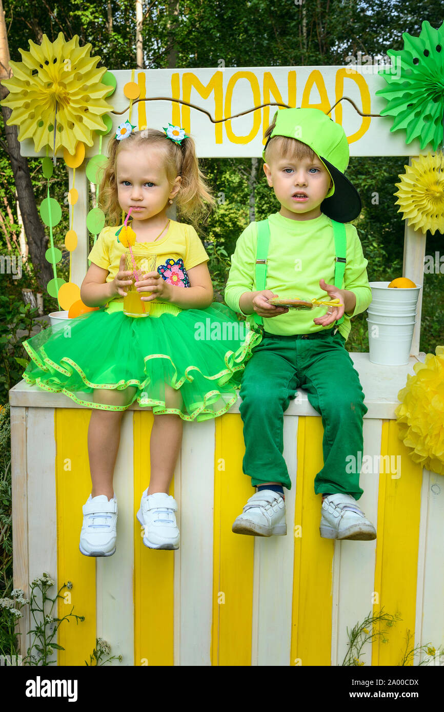Little boy and girl sitting on lemonade stand in park in summer day ...