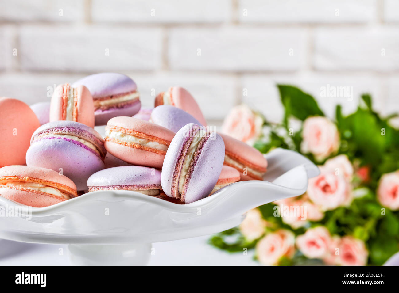 close-up of macarons on a white platter. beautiful bouquet of roses and ...