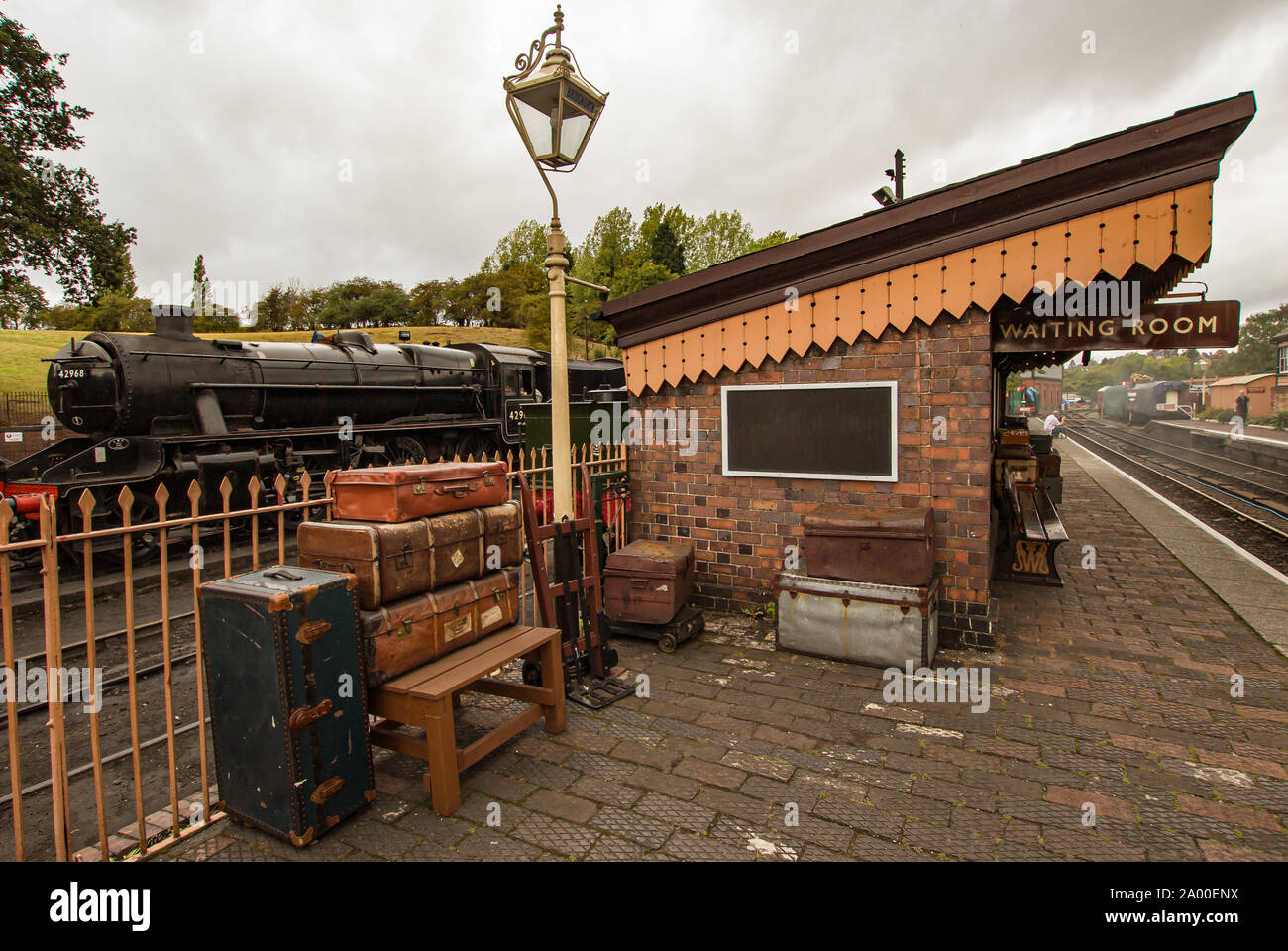 Waiting room on railway platform with steam train behind and luggage ...