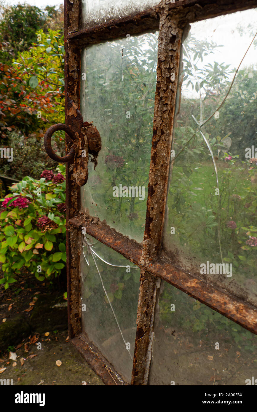 Old rusty window with cracked glass panes opening onto a garden Stock ...