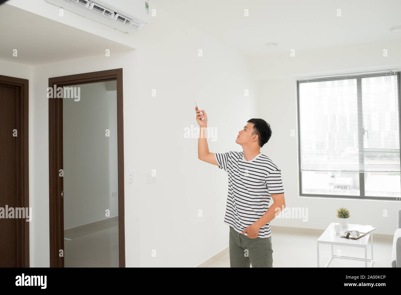 Air conditioner inside unit with man operating remote controller. / Air ...